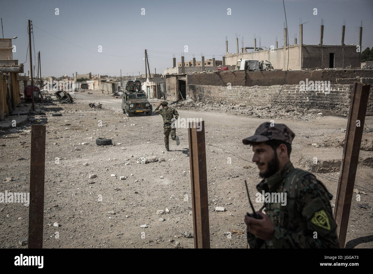 Soldiers of the Syrian Democratic Forces (SDF) cross a street in Al ...