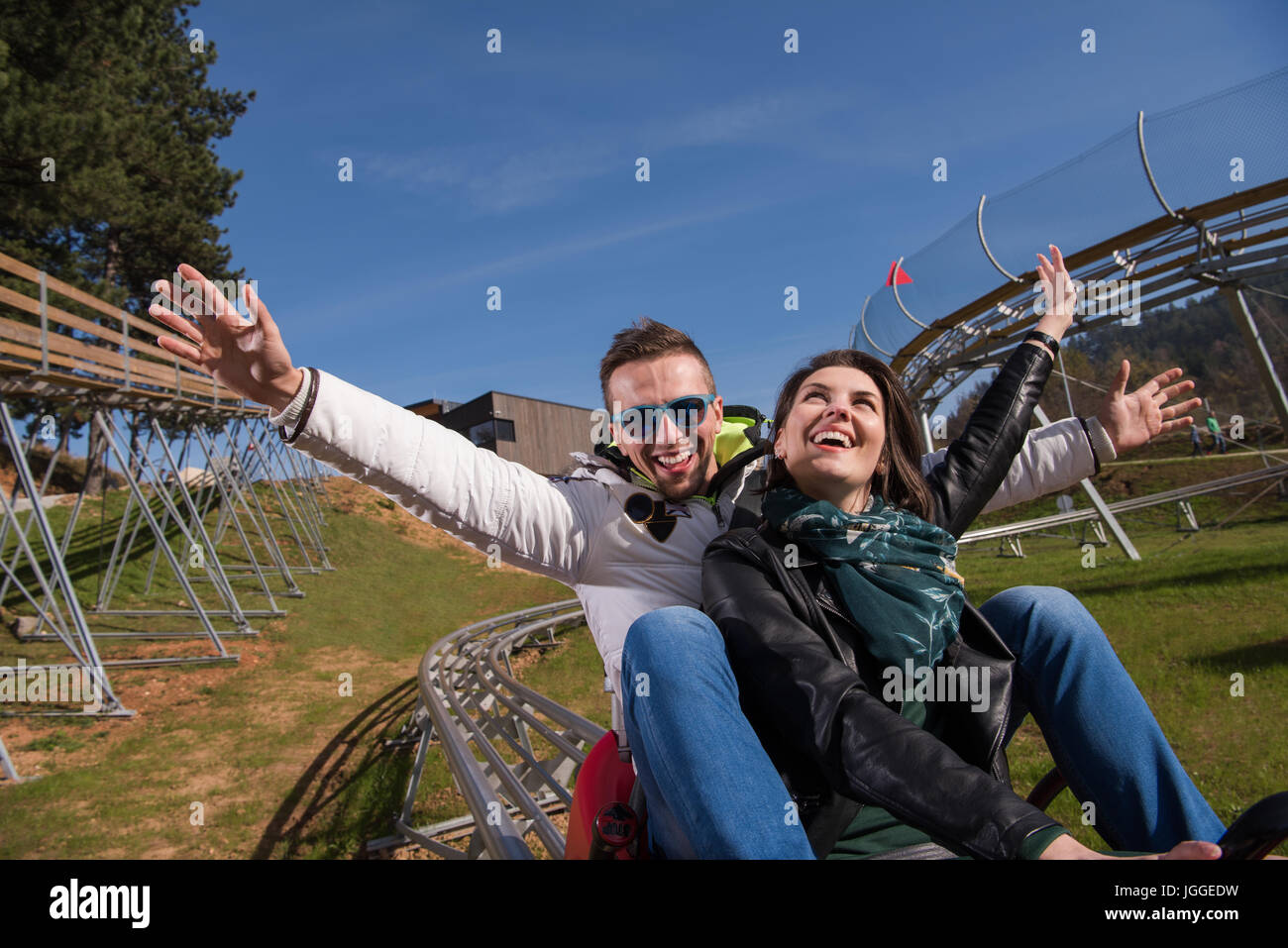 Excited young couple enjoys driving on alpine coaster Stock Photo - Alamy