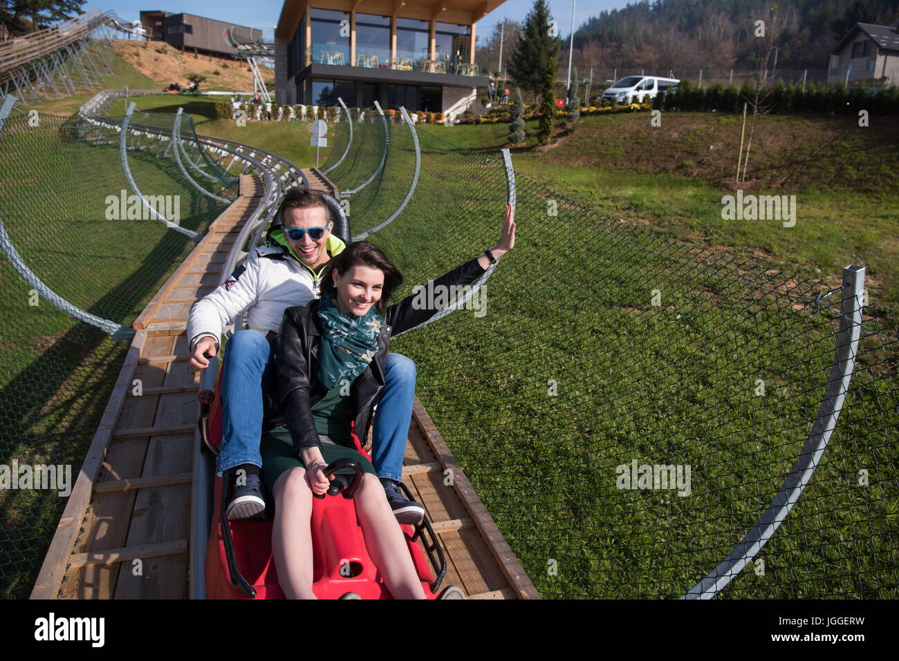 Excited young couple enjoys driving on alpine coaster Stock Photo - Alamy