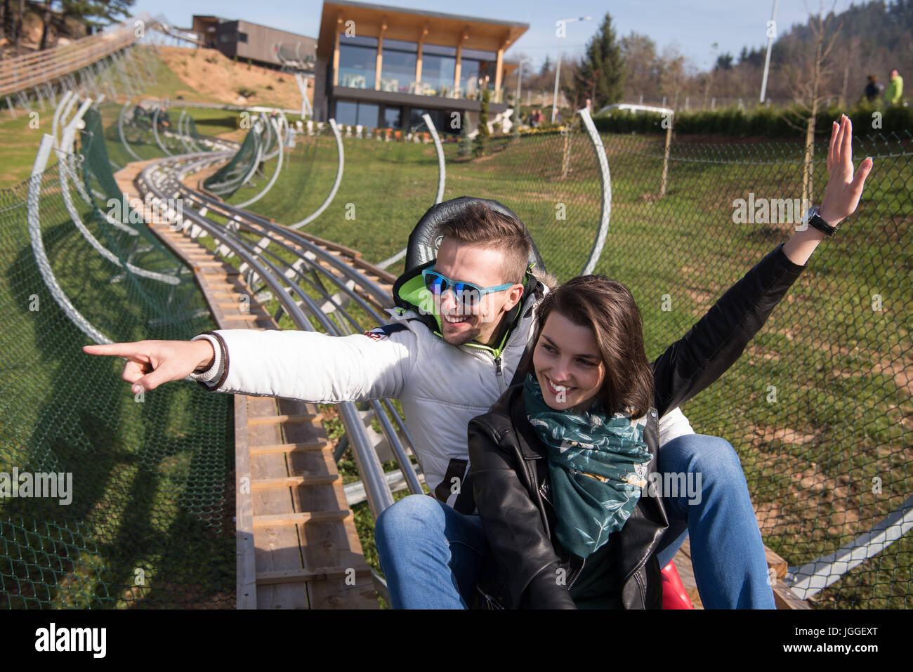 Excited young couple enjoys driving on alpine coaster Stock Photo - Alamy
