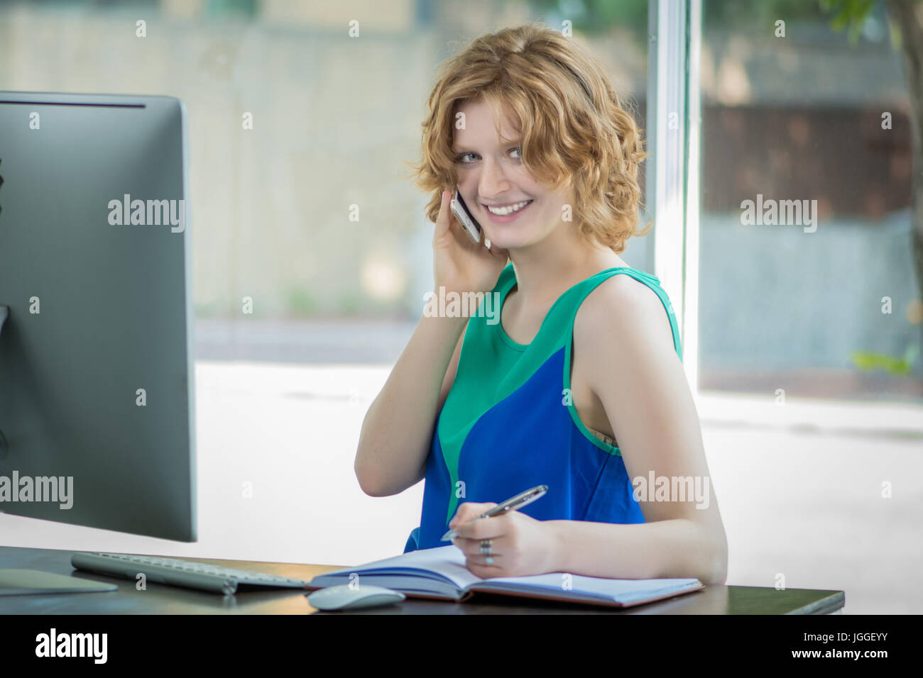 Smiling girl sitting at computer desk Stock Photo - Alamy