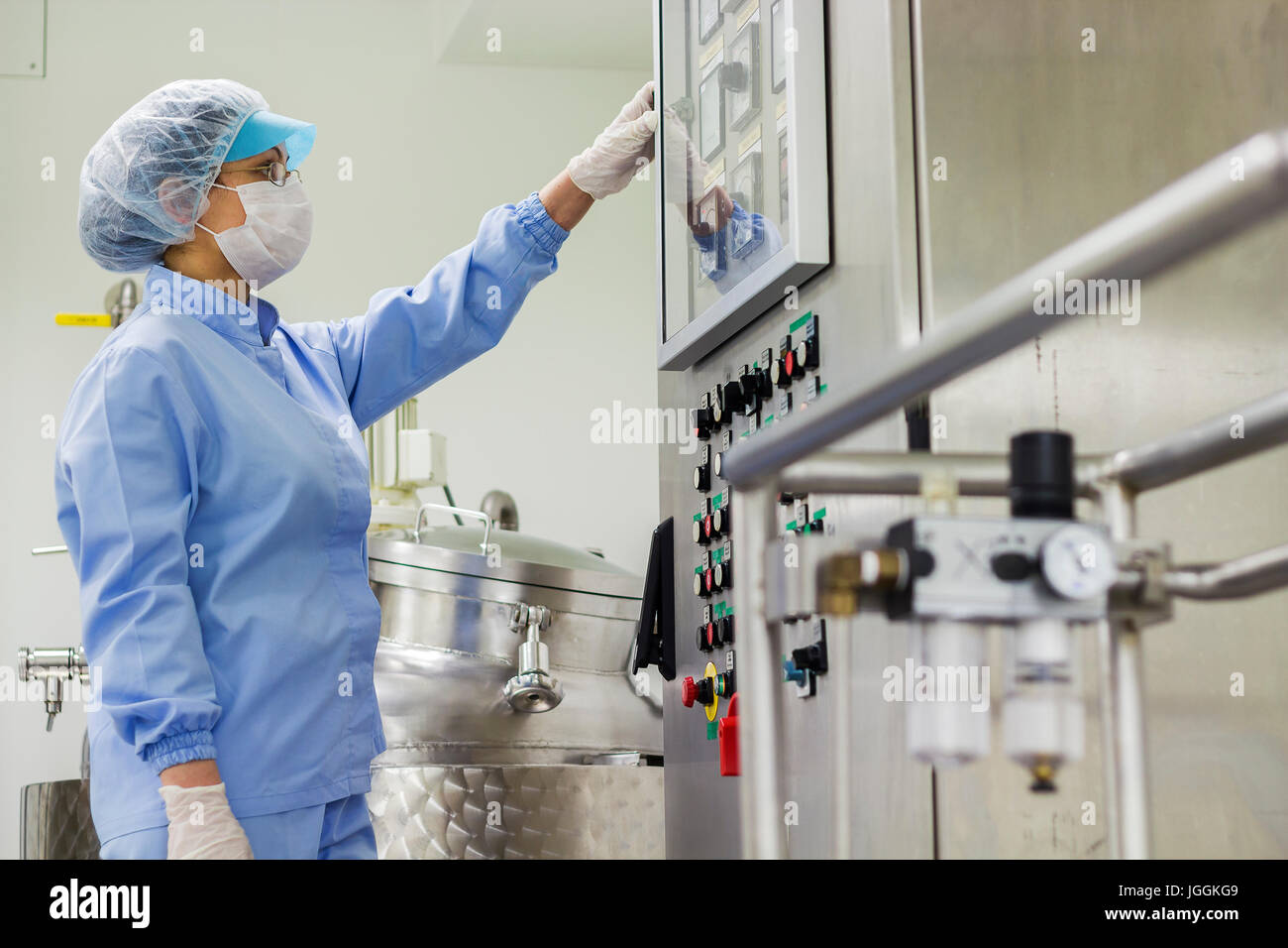 Female worker at pharmaceutical factory operating control panel of the ...