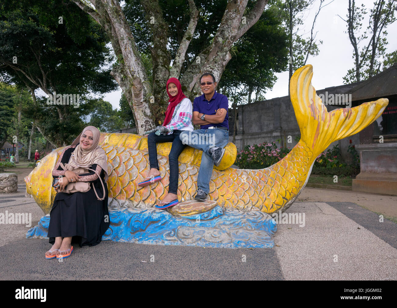 Indonesian tourists posing on a giant fish sculpture in temple Pura ...