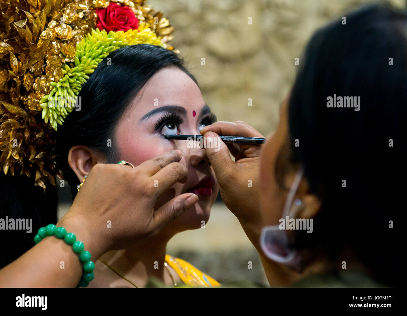 A woman applying makeup to a teenage girl in traditional costume before ...
