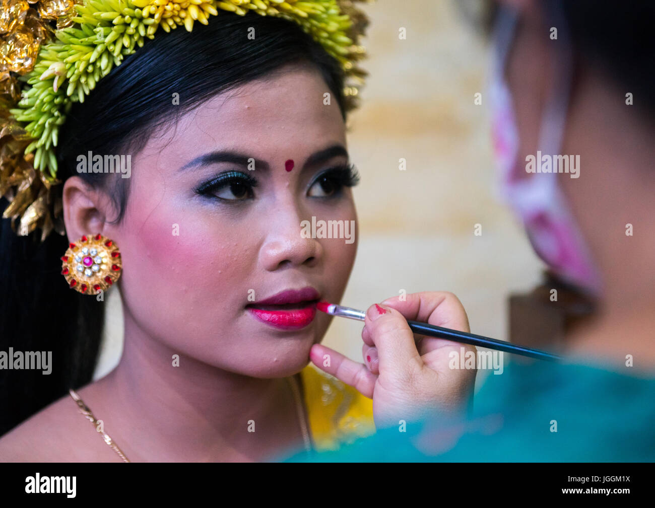 A woman applying makeup to a teenage girl in traditional costume before ...