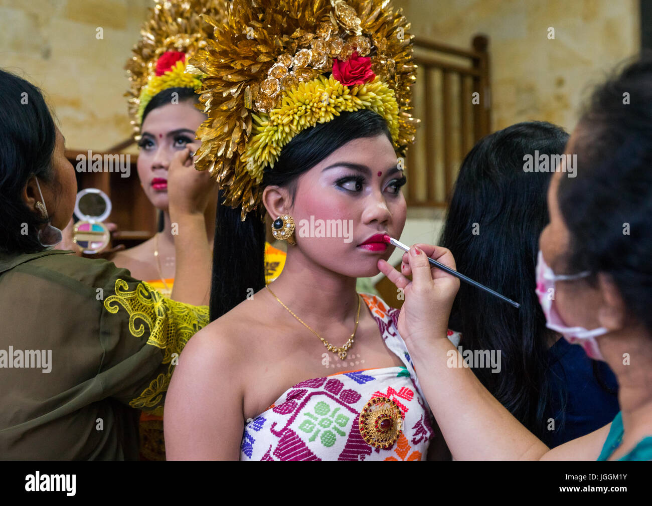 A woman applying makeup to a teenage girl in traditional costume before ...
