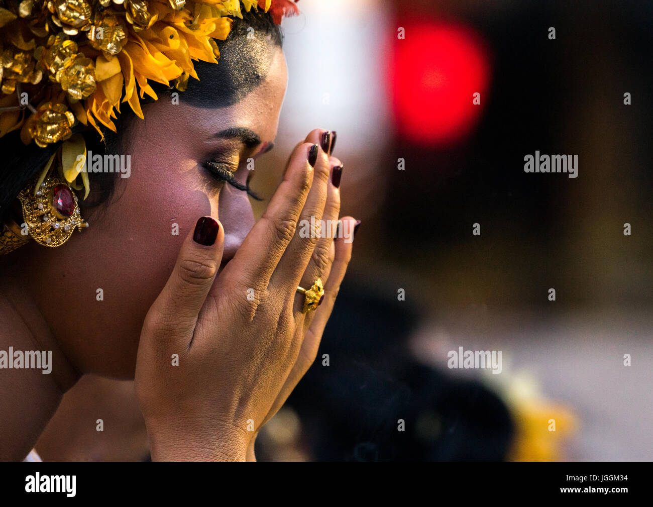 A teenage girl in traditional costume praying before a tooth filing ...