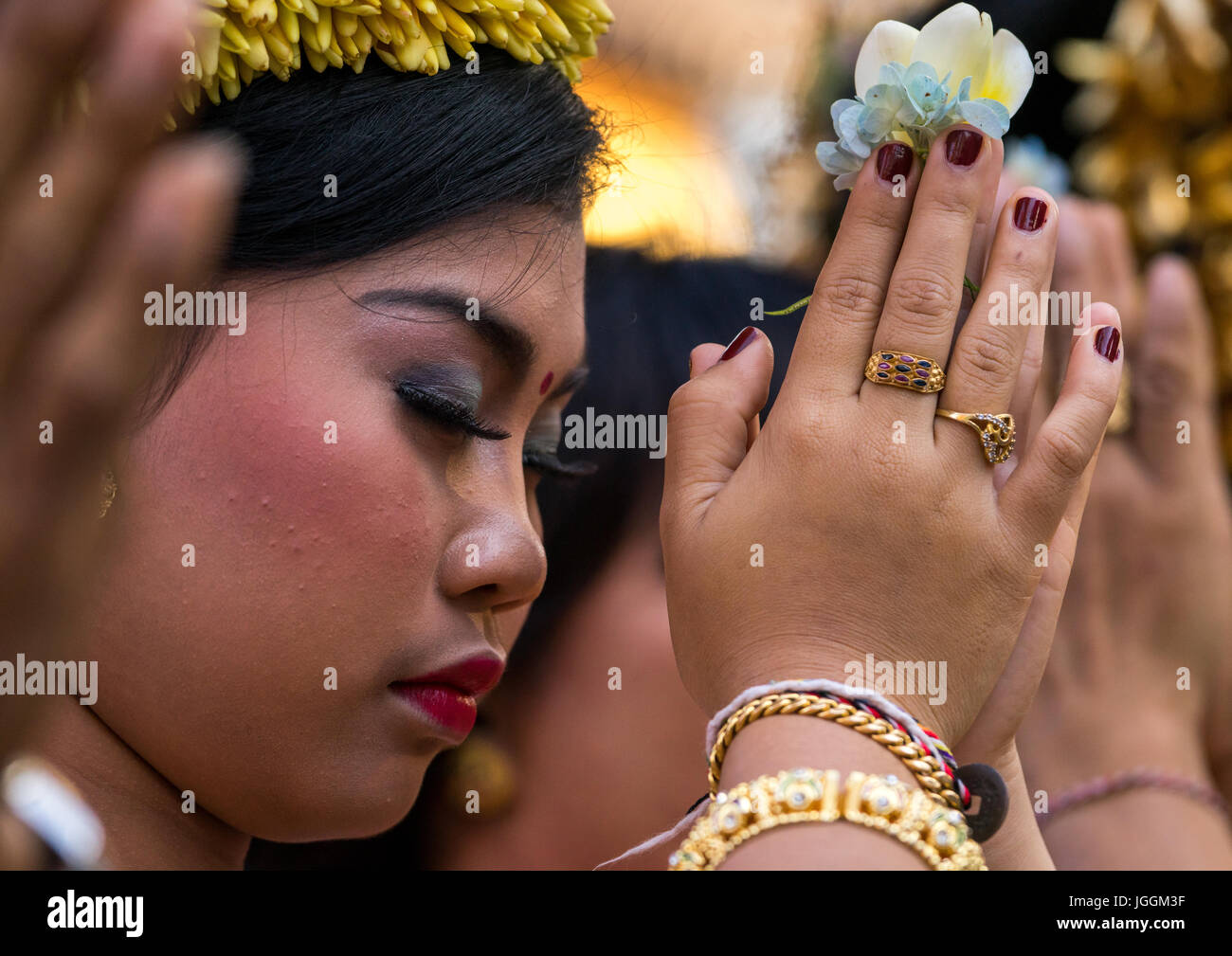 A teenage girl in traditional costume praying before a tooth filing ...
