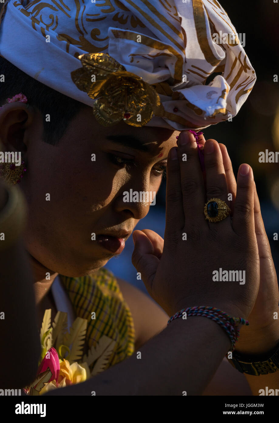 A teenage boy in traditional costume praying before a tooth filing ...