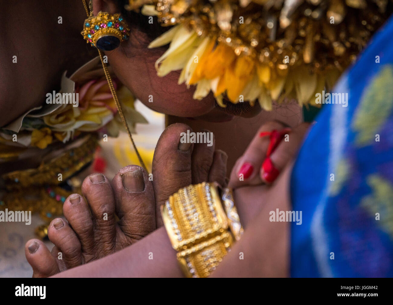 A teenage girl in traditional costume paying respect to her mother ...