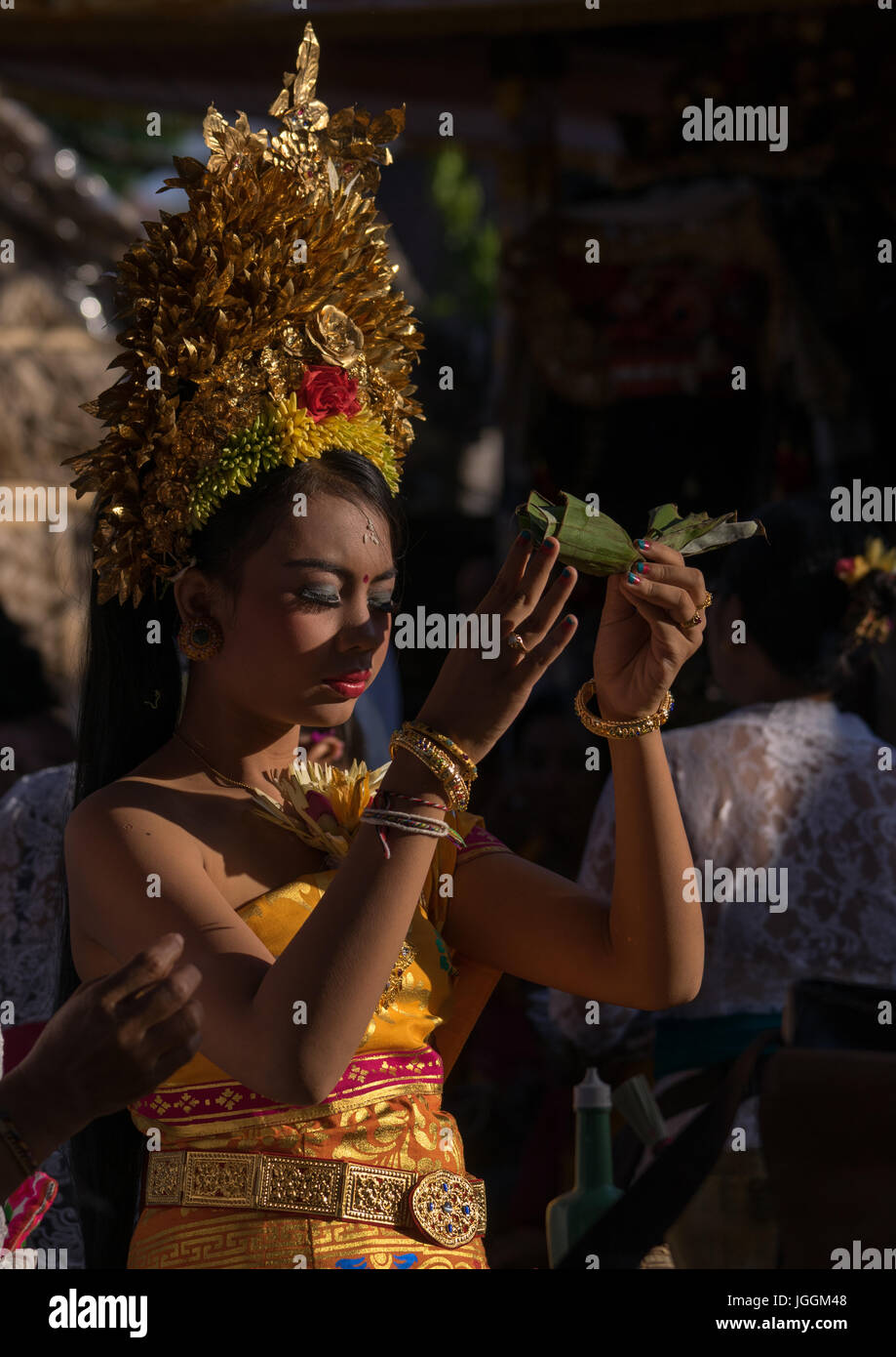 A teenage girl in traditional costume praying before a tooth filing ...
