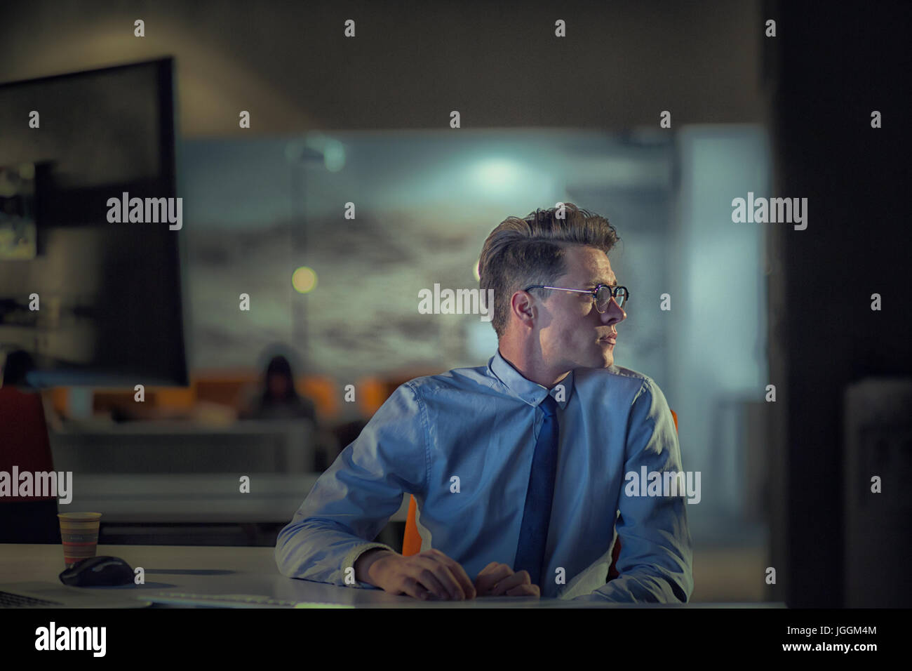 Young man working on computer at night in dark office. The designer ...
