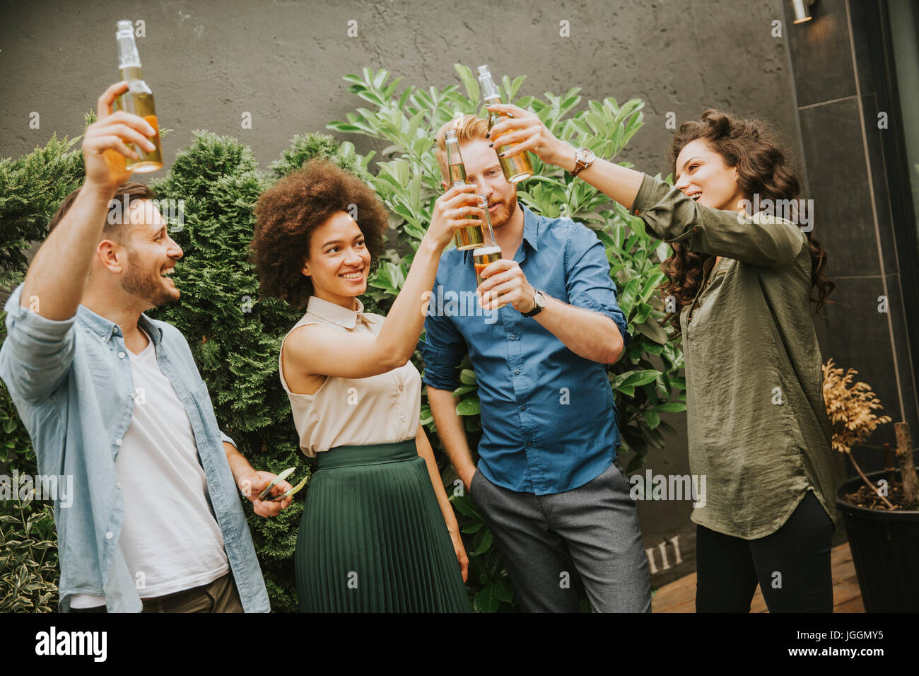 Group of friends having outdoor garden party toast with alcoholic cider ...
