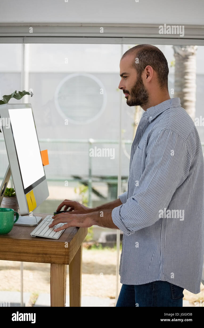 Side view of male designer using computer while standing in studio ...