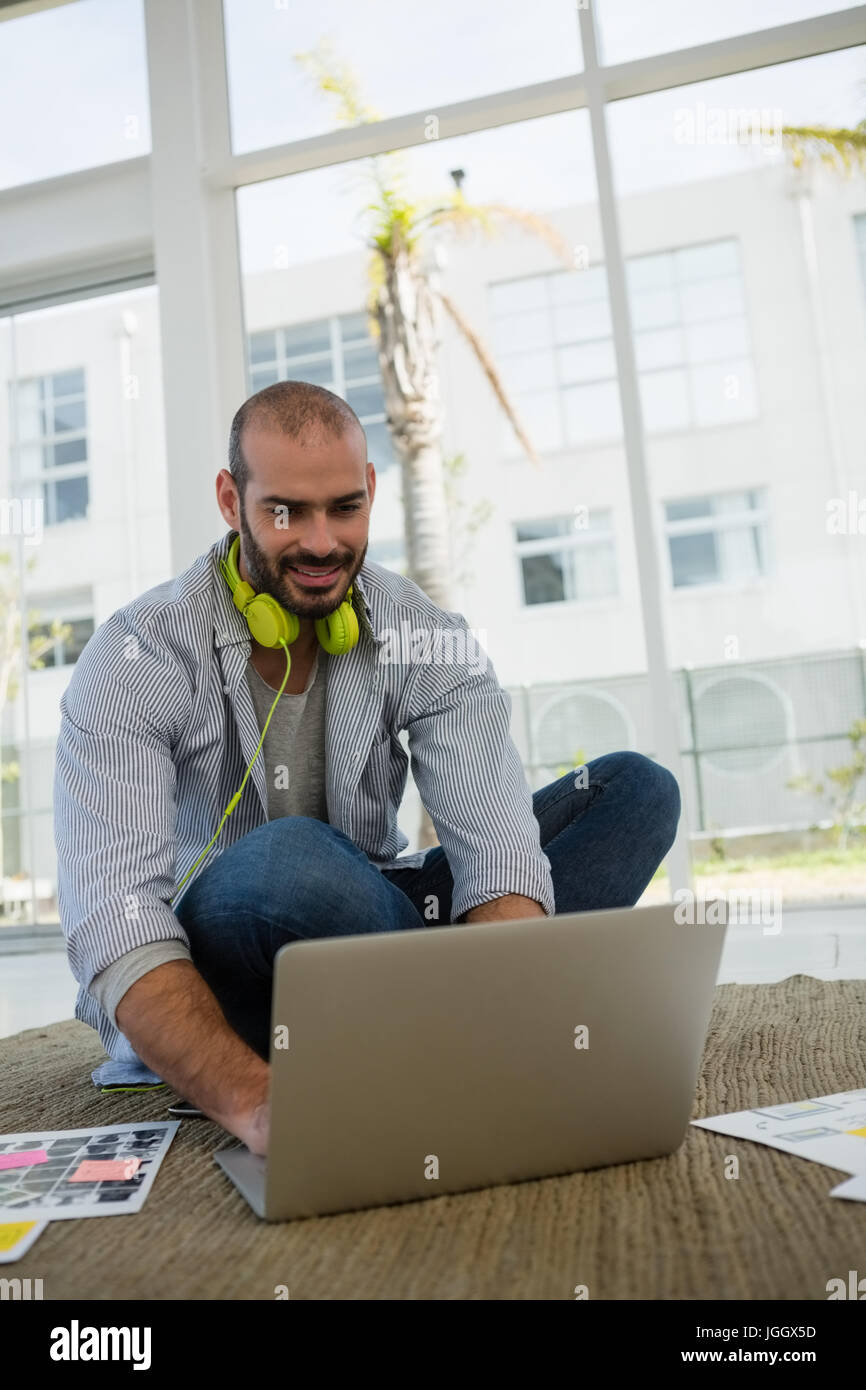 Designer using laptop while sitting on floor at studio Stock Photo - Alamy