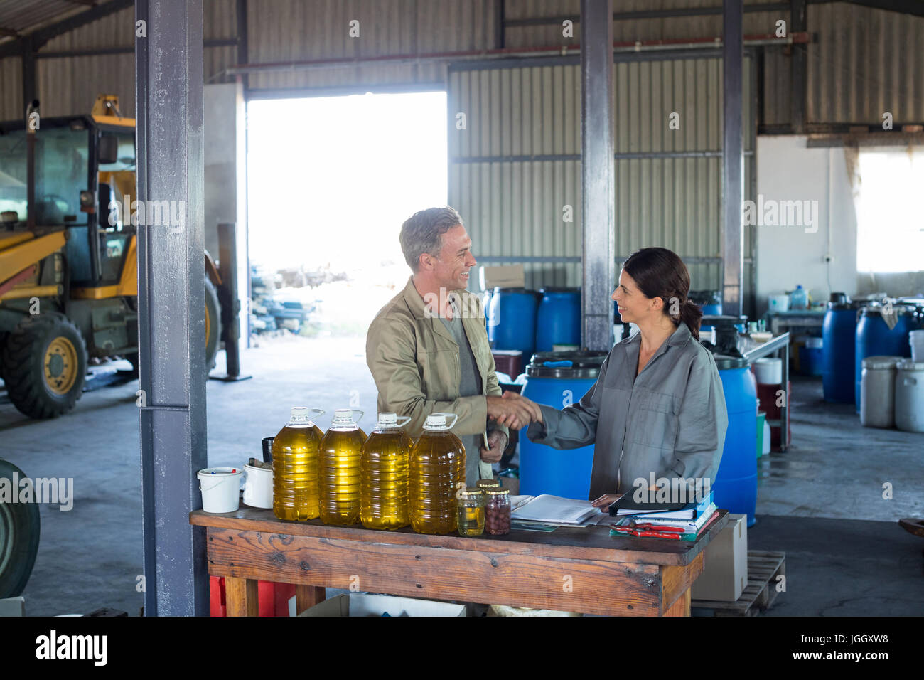 Smiling workers shaking hand in olive factory Stock Photo - Alamy