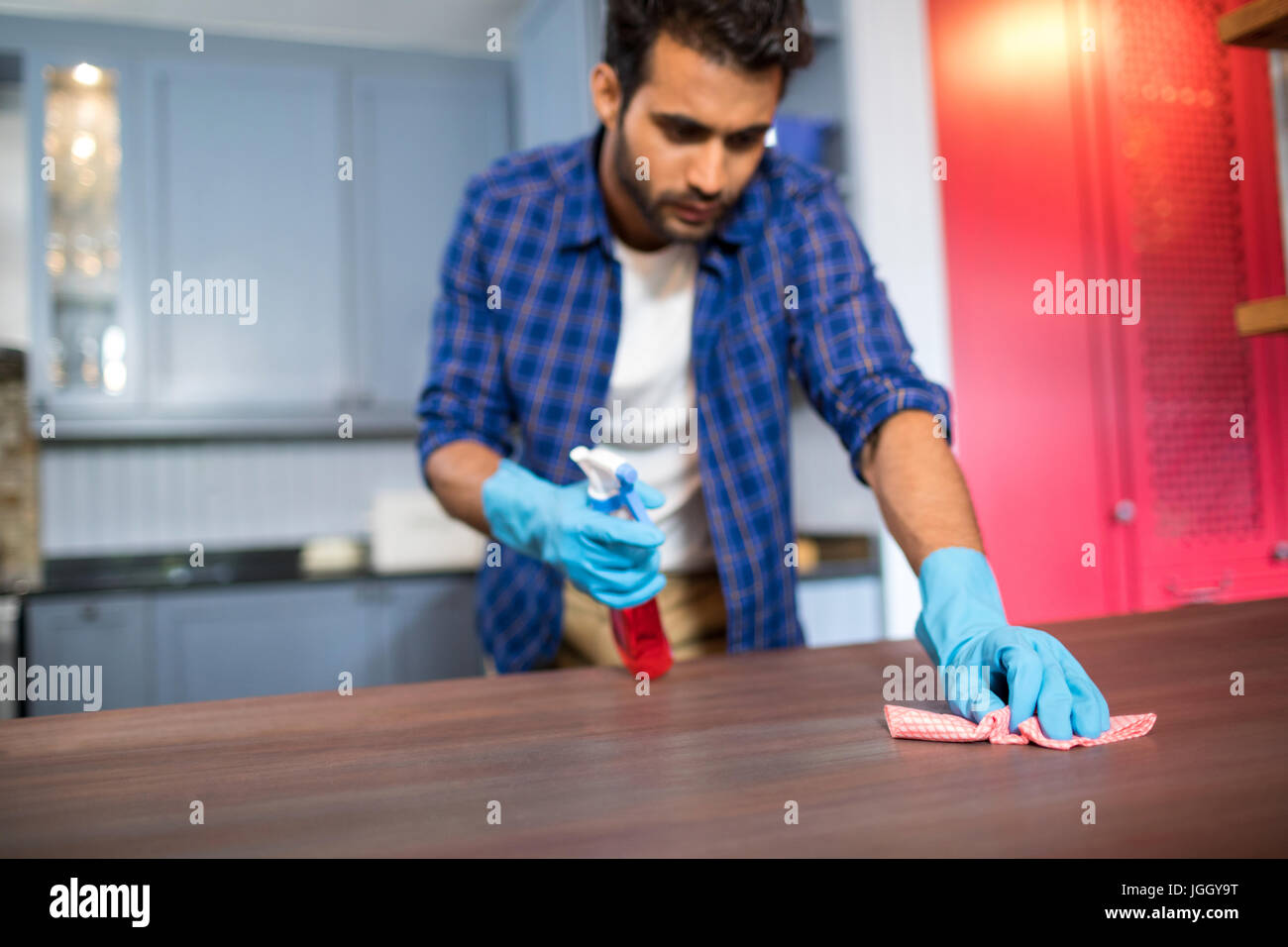 Young man cleaning wooden table at home Stock Photo - Alamy