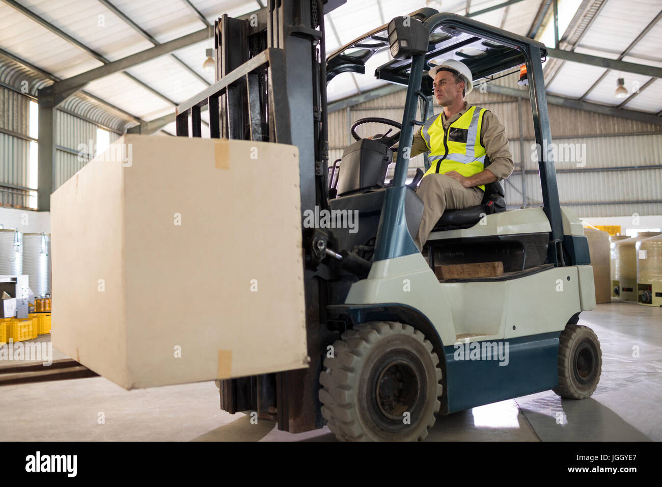 Worker carrying package with forklift in oil factory Stock Photo - Alamy
