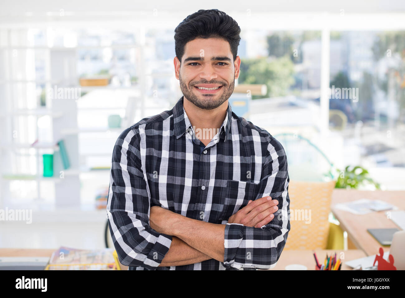 Portrait of male executive standing with arms crossed in the office ...