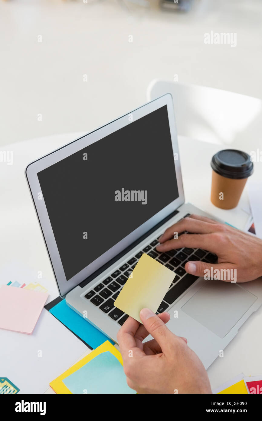 Cropped hands of graphic designer holding adhesive note while using ...