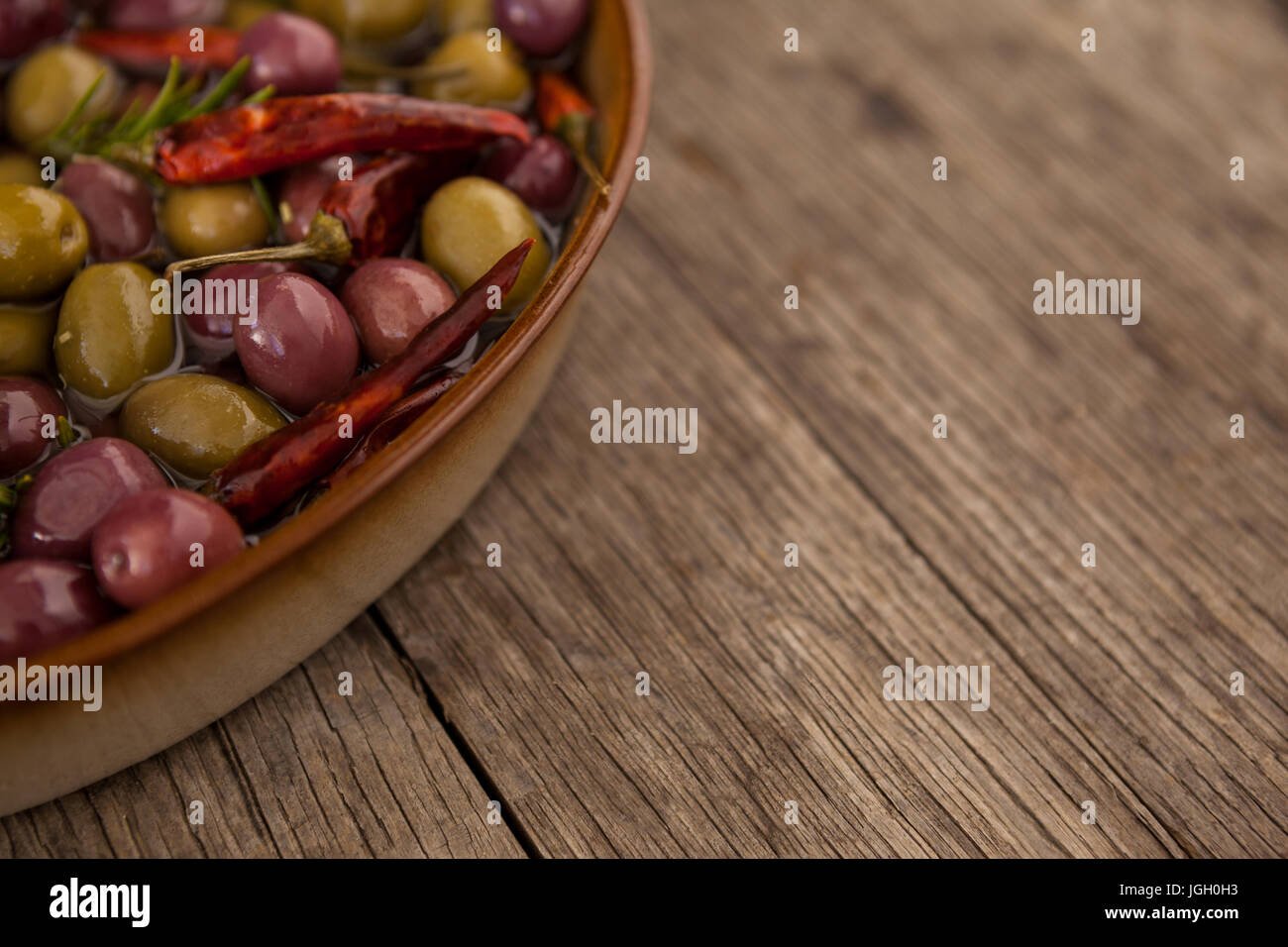Cropped image of olives with oil and chili pepper in container on ...