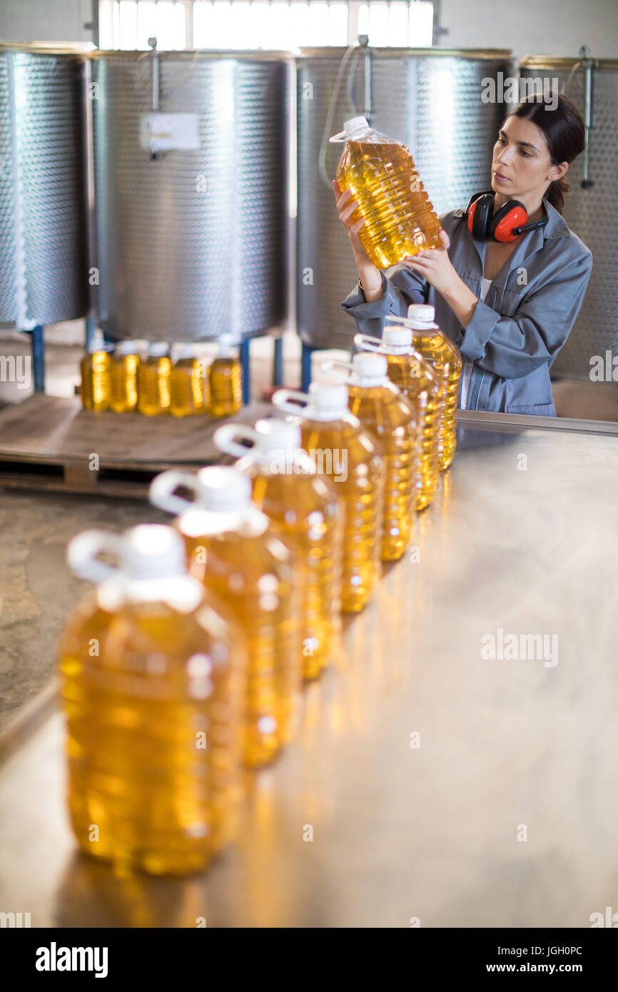 Female worker checking oil bottles in factory Stock Photo - Alamy