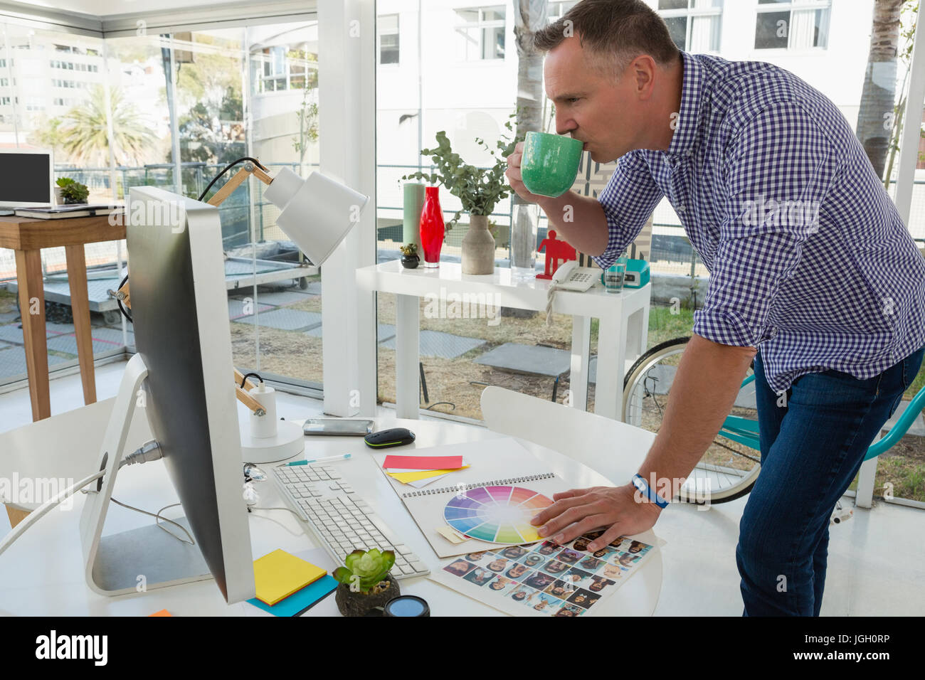 Designer looking at computer while having drink in studio Stock Photo ...
