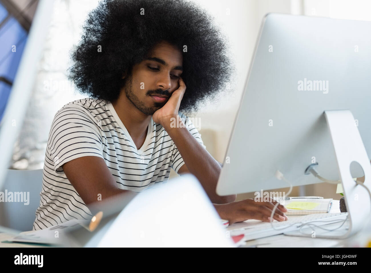 Young man using computer at desk in creative office Stock Photo - Alamy