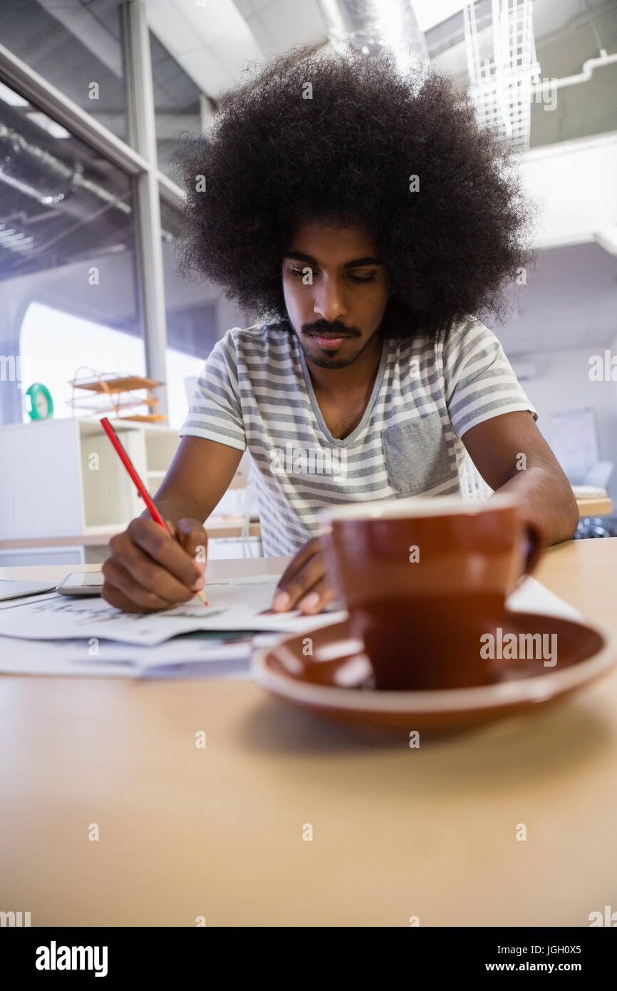 Young man writing on document at desk in office Stock Photo - Alamy