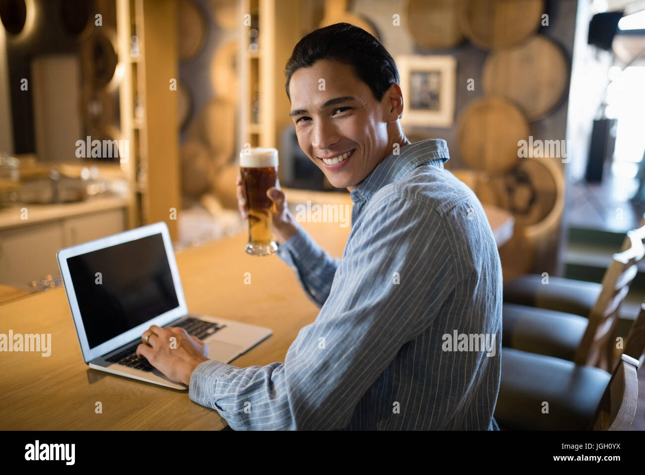 Portrait of man using laptop while having beer in bar Stock Photo - Alamy