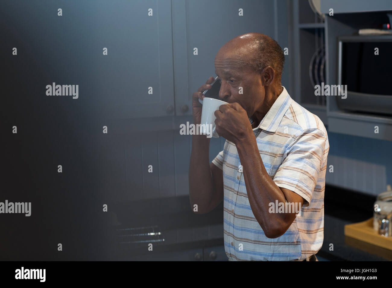 Man having coffee while talking on phone in kitchen at home Stock Photo ...