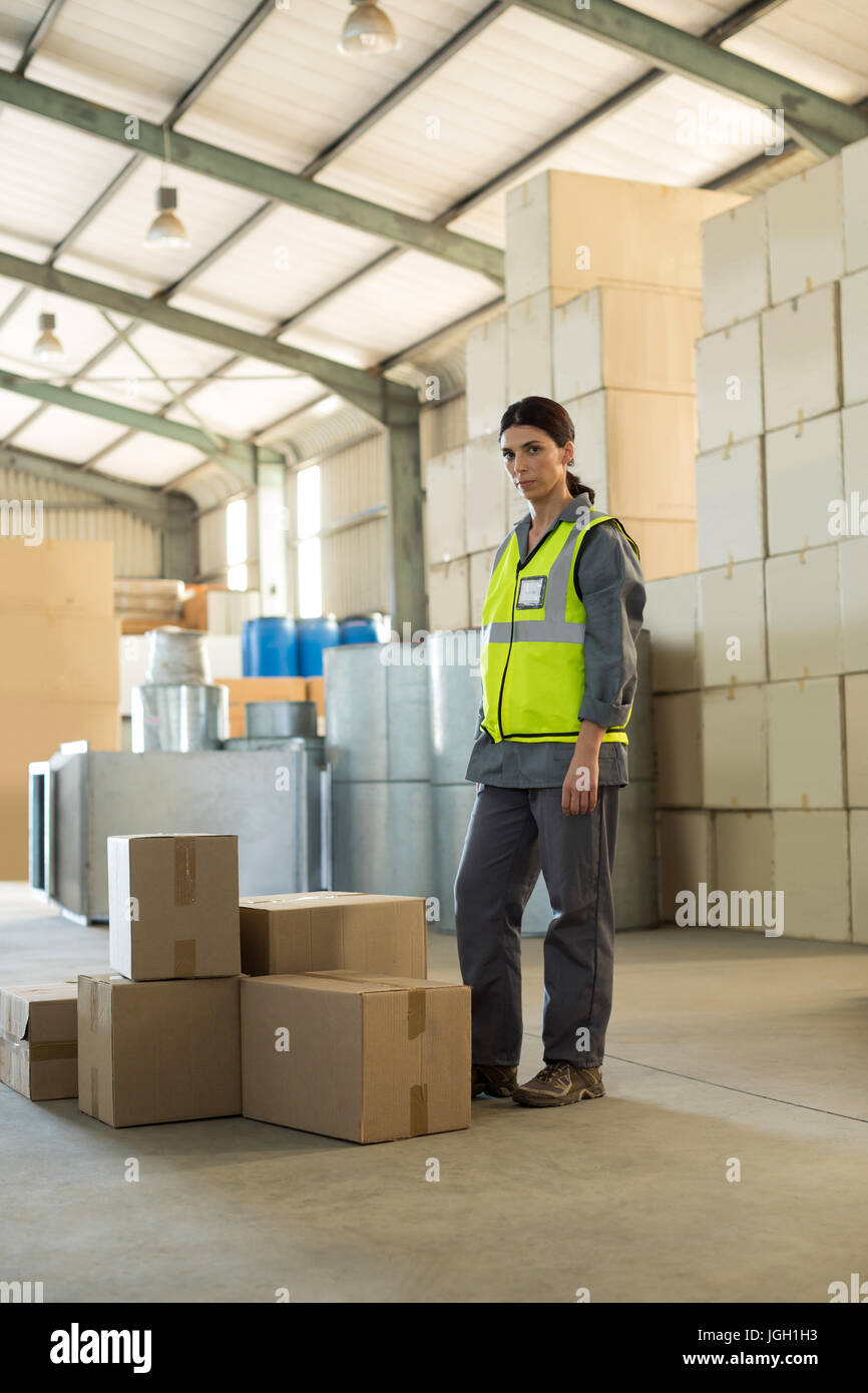 Portrait of female worker standing near boxes in factory Stock Photo ...