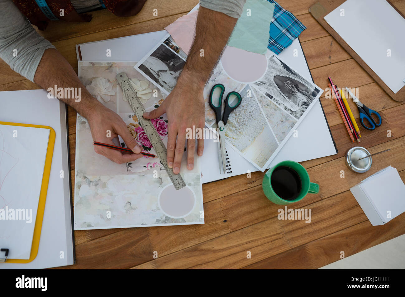 Cropped hands of designer drawing line on paper at table in office ...