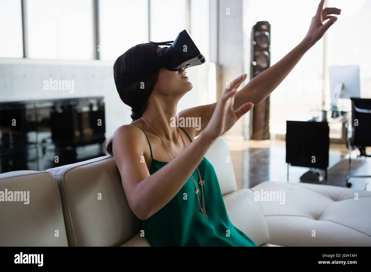 Businesswoman using virtual reality simulator while sitting on sofa at ...