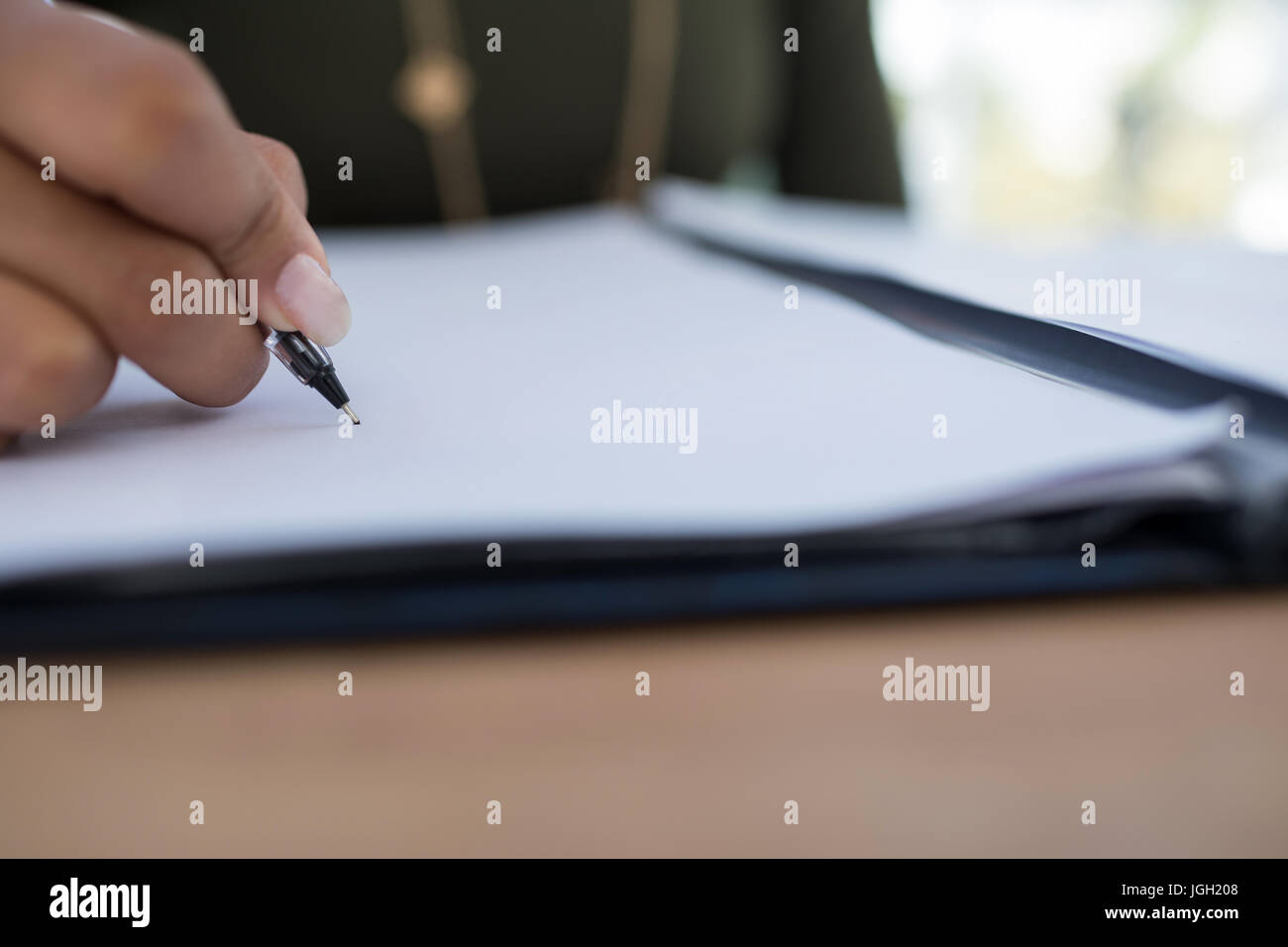 Mid-section of female executive writing on a document at desk in the ...