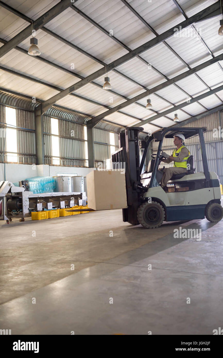 Worker carrying package with forklift in oil factory Stock Photo - Alamy
