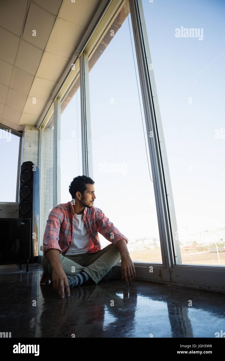 Thoughtful young businessman looking through window at office Stock ... Thoughtful young businessman looking through window at office Stock ...