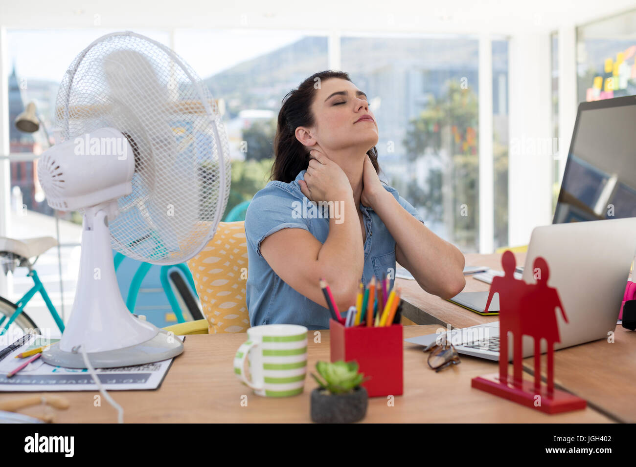 Female executive enjoying breeze from table fan in the office Stock ...