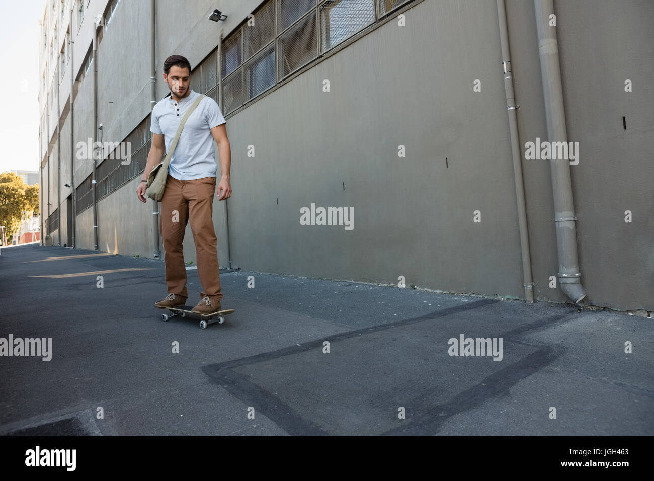 Full length of young man skating on footpath by building Stock Photo ...