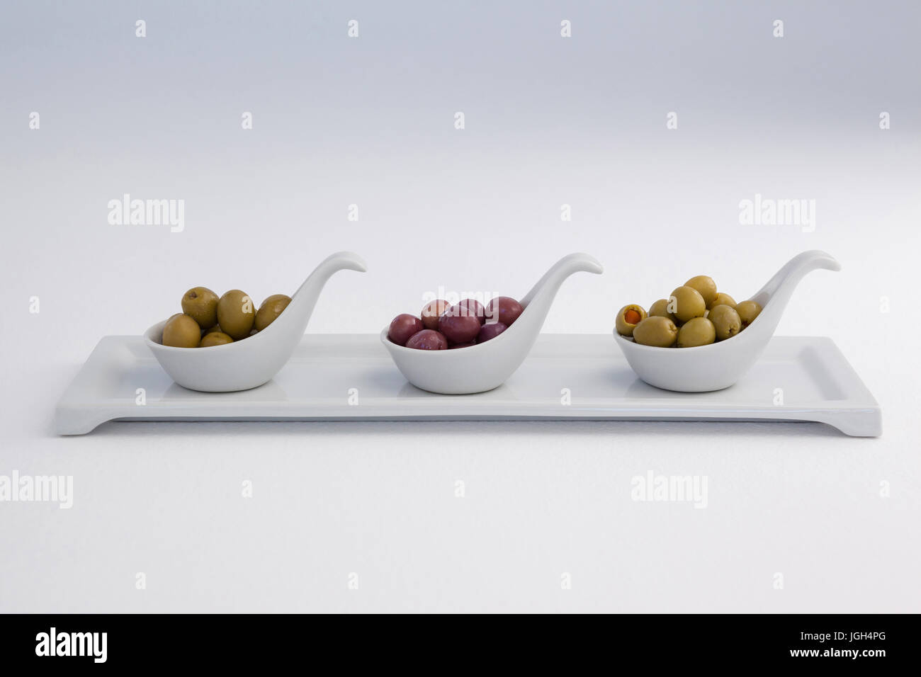 Various olives in container on tray against white background Stock ...