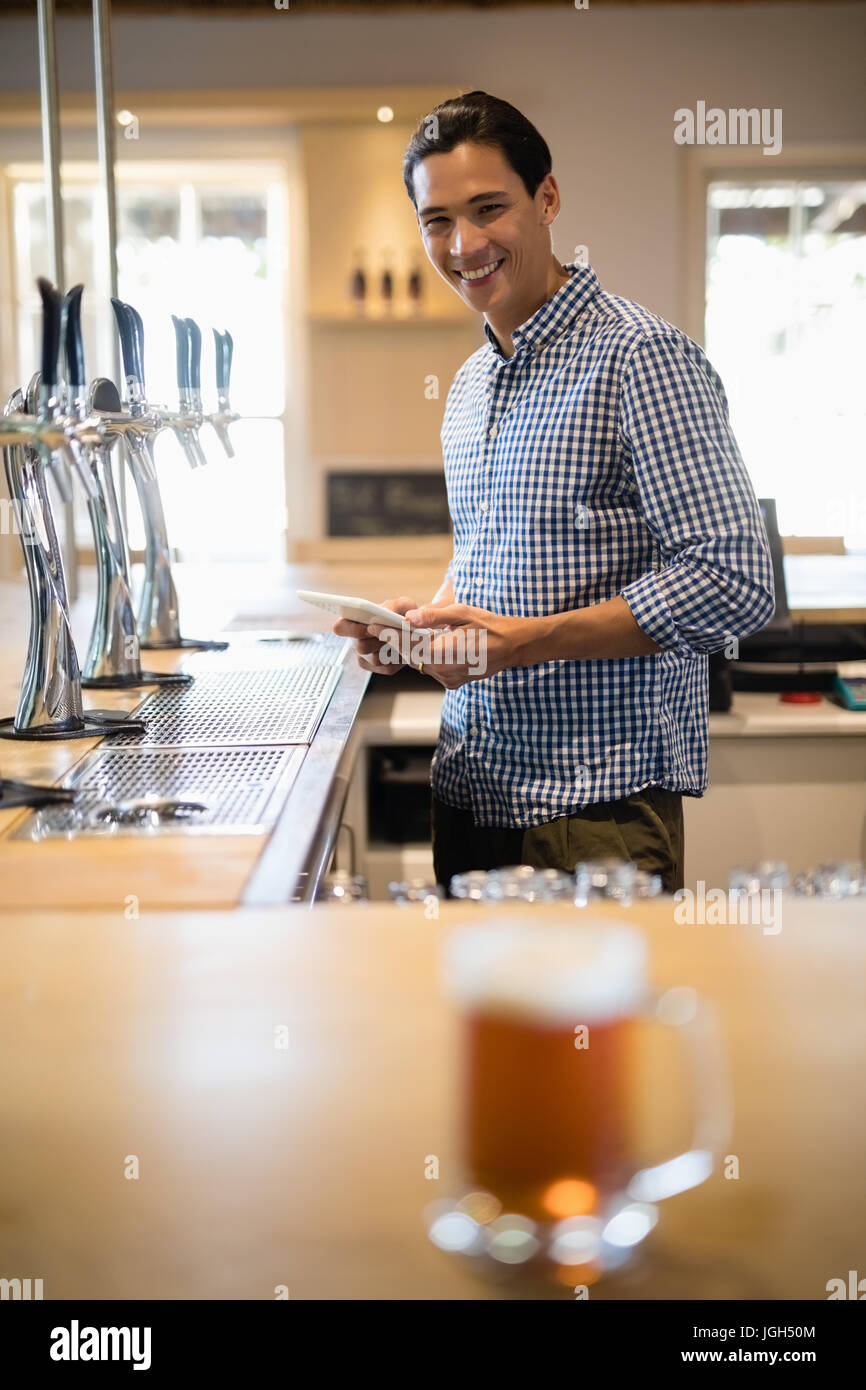 Portrait of bar tender holding digital tablet at counter in restaurant ...