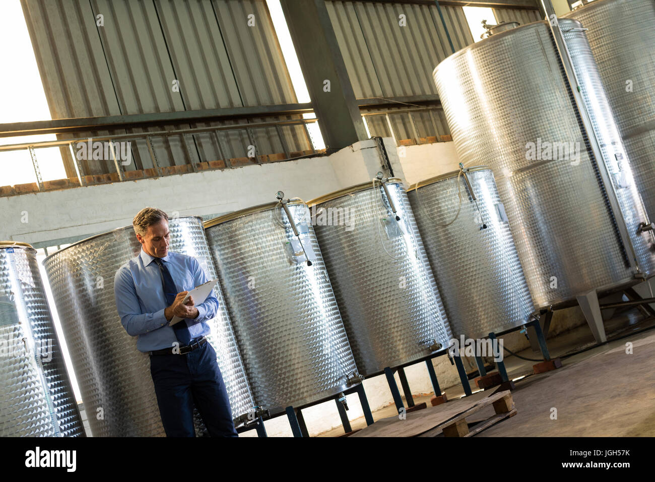 Attentive manager writing in clipboard at factory Stock Photo - Alamy