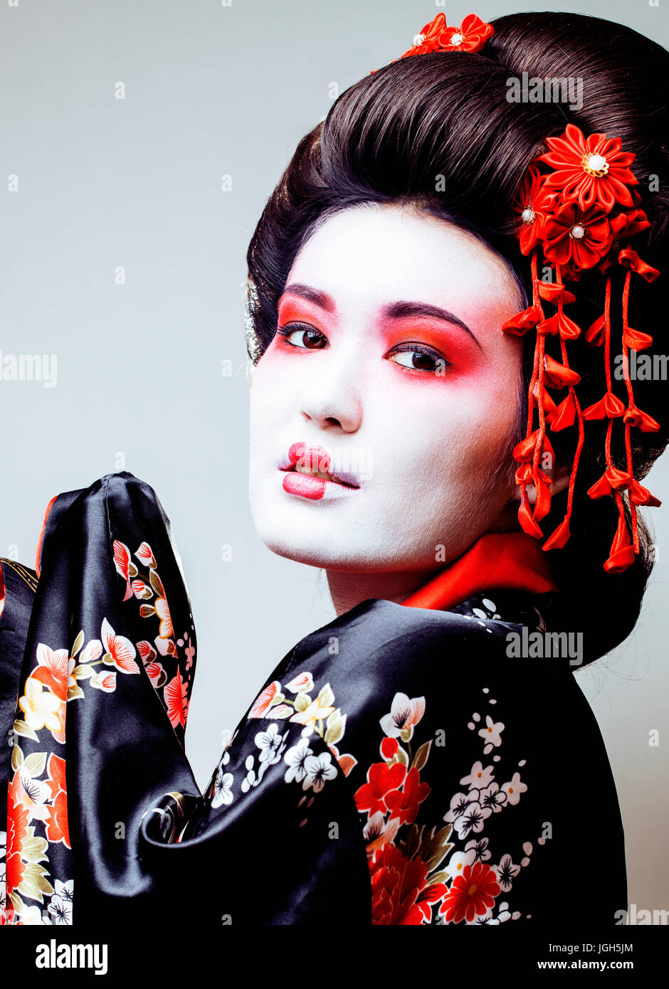 young pretty geisha in black kimono among sakura, asian ethno close up ...