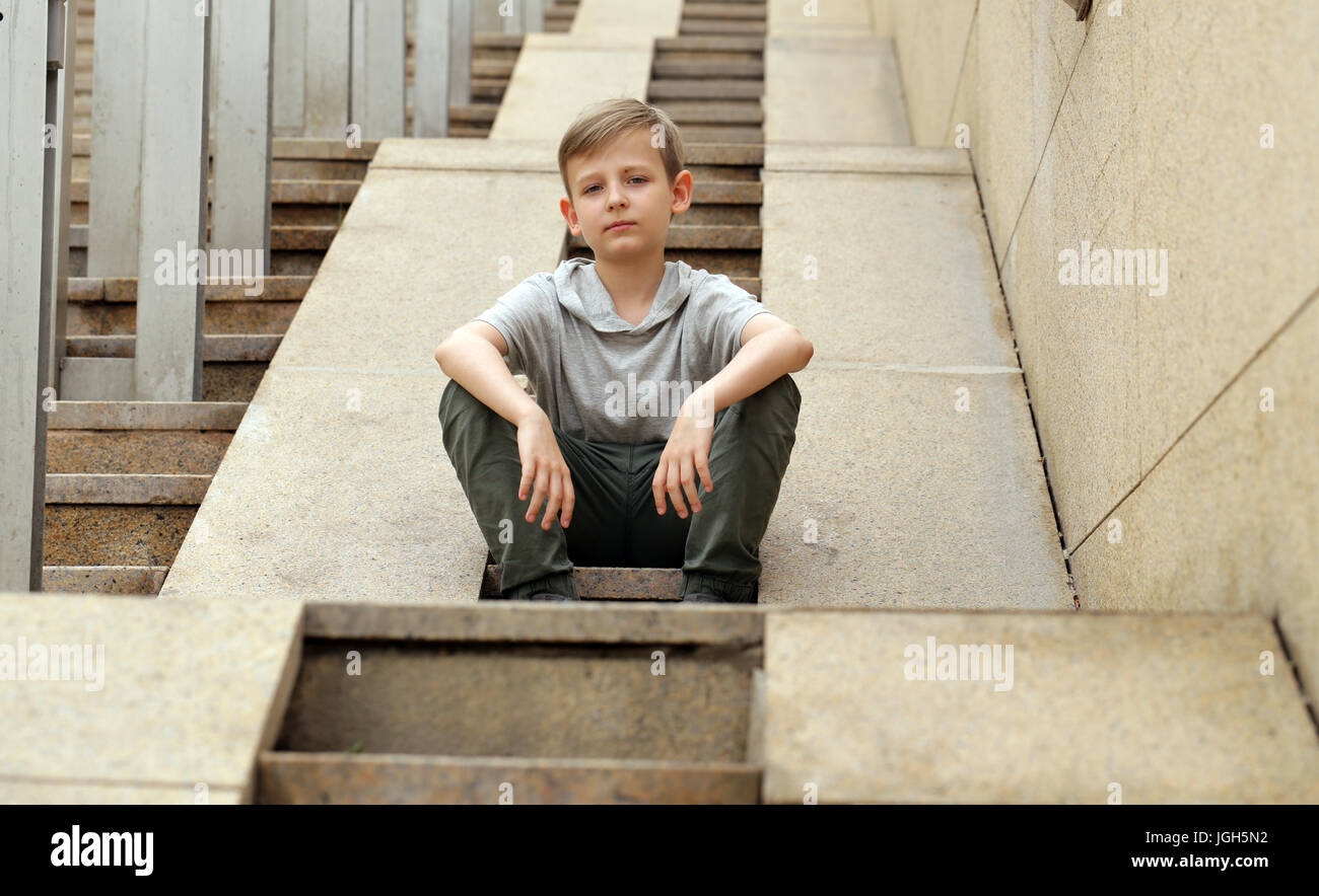 Sad boy sits on a large granite staircase - urban style Stock Photo - Alamy