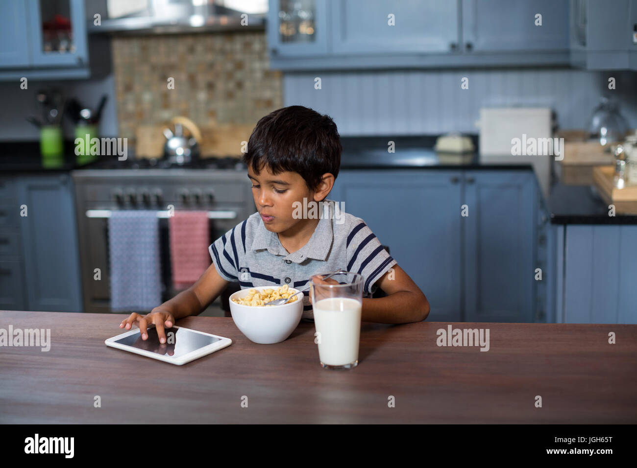 Boy using digital tablet while having cereal breakfast at home Stock ...