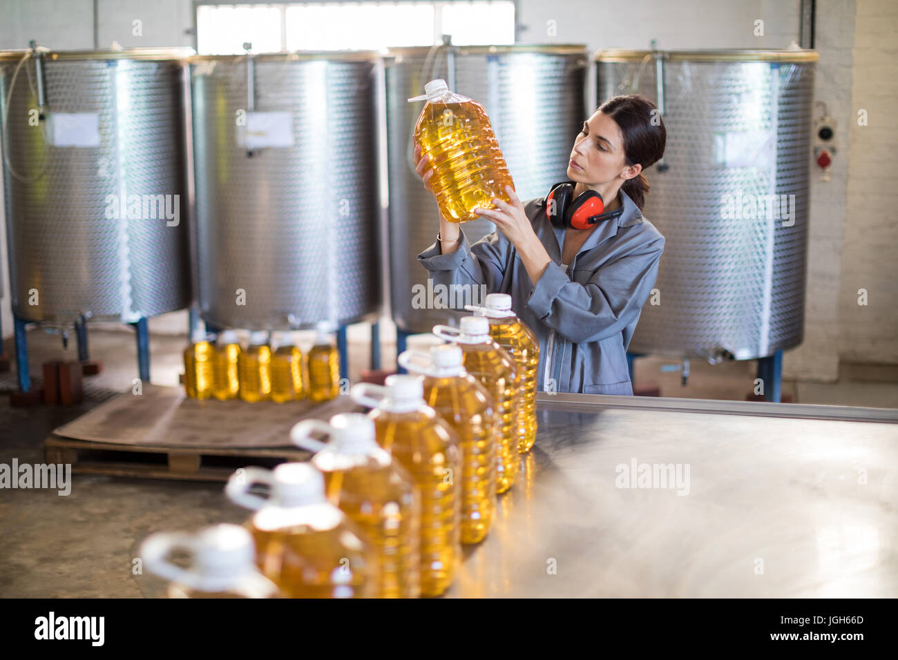 Female worker checking oil bottles in factory Stock Photo - Alamy