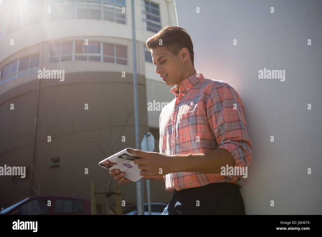 Side view of man reading paper while standing by wall Stock Photo - Alamy