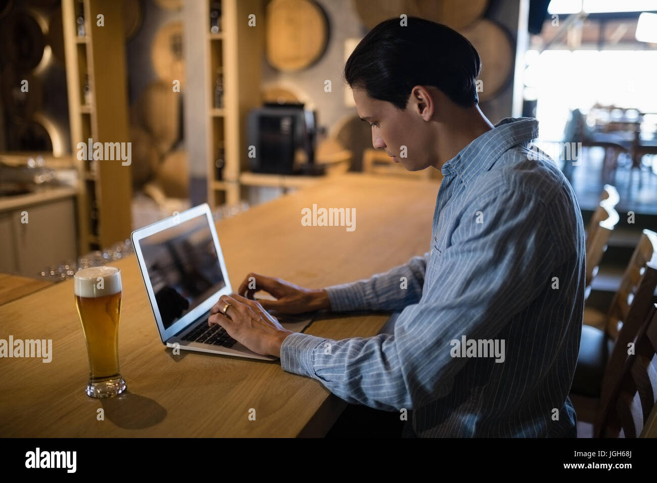 Man using laptop while having beer in bar Stock Photo - Alamy