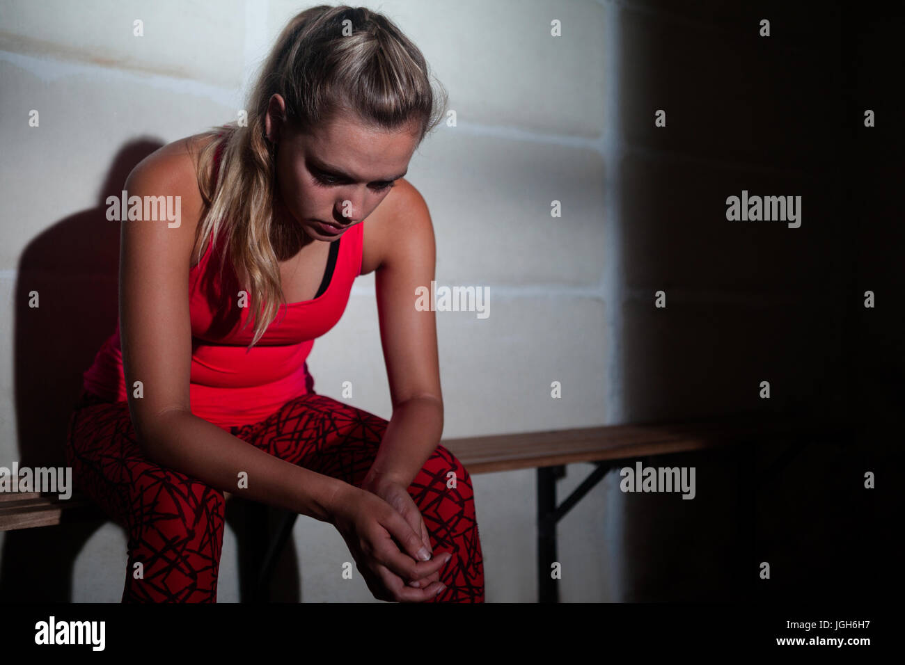 Sad woman relaxing on bench in fitness studio Stock Photo - Alamy