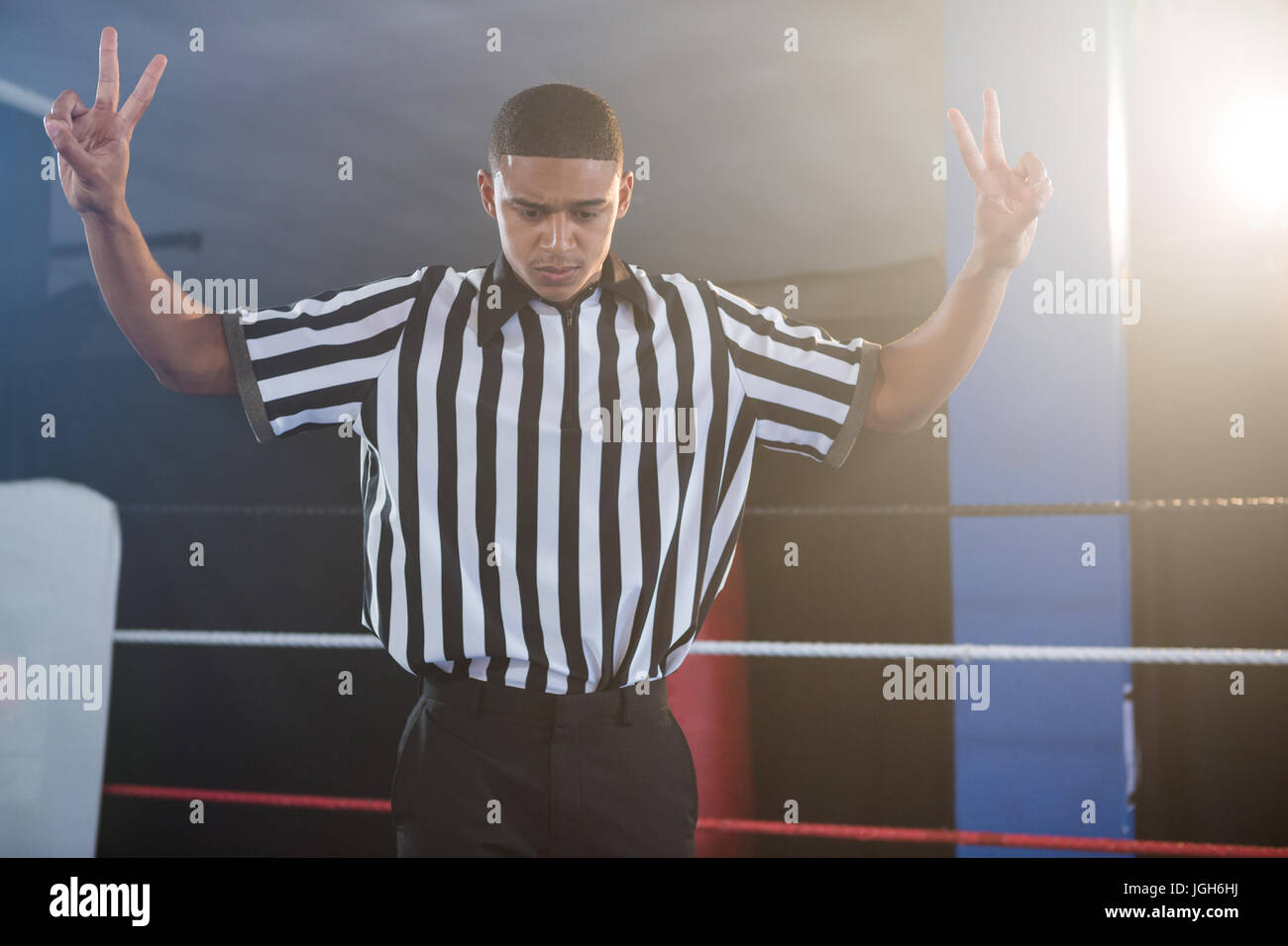 Young male referee gesturing while looking down in boxing ring at ...